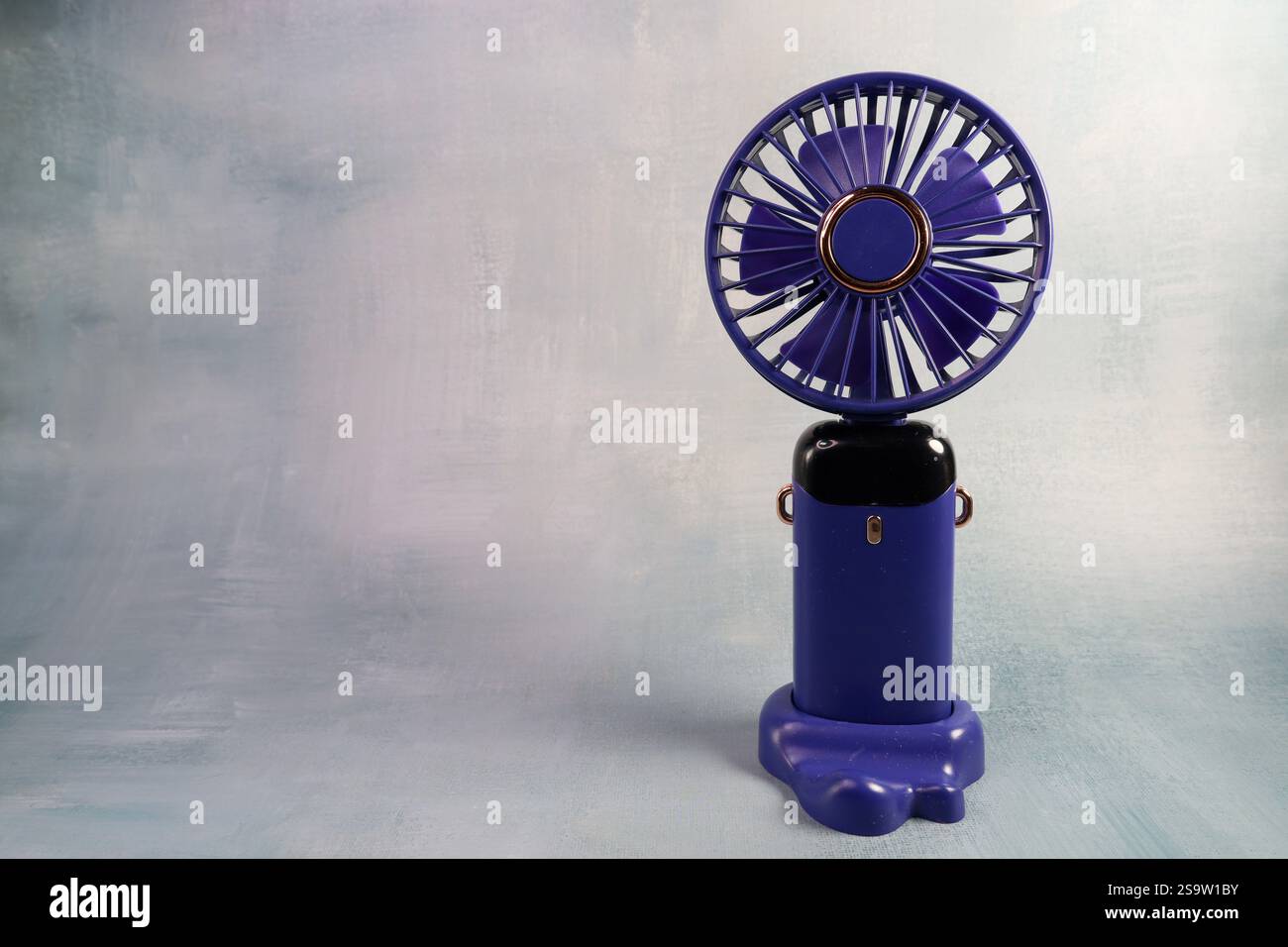 Small Blue Fan Positioned on a Textured Gray Background Stock Photo - Alamy
