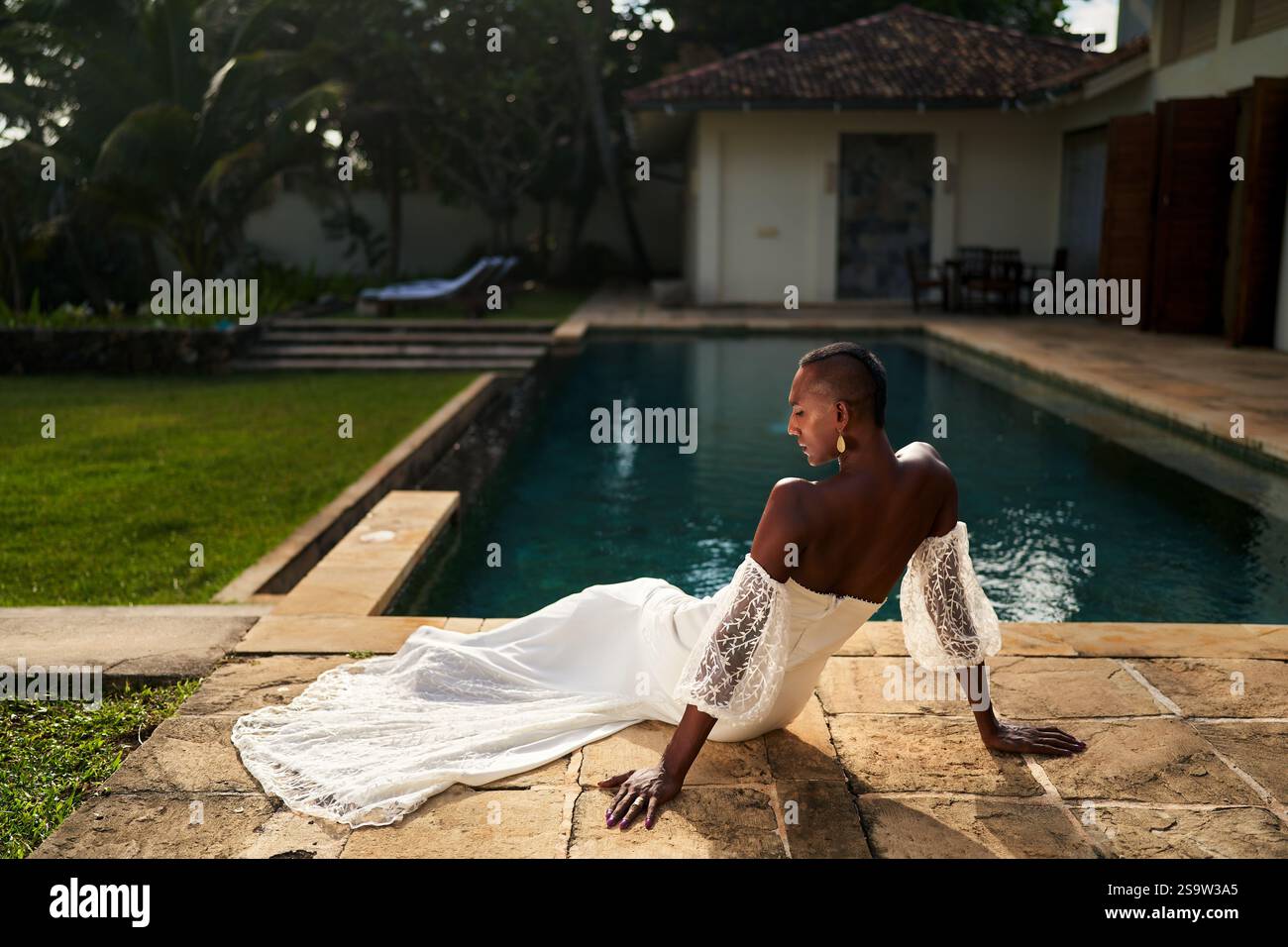 Person in white bridal dress lounges by villa pool. Gender fluid ...