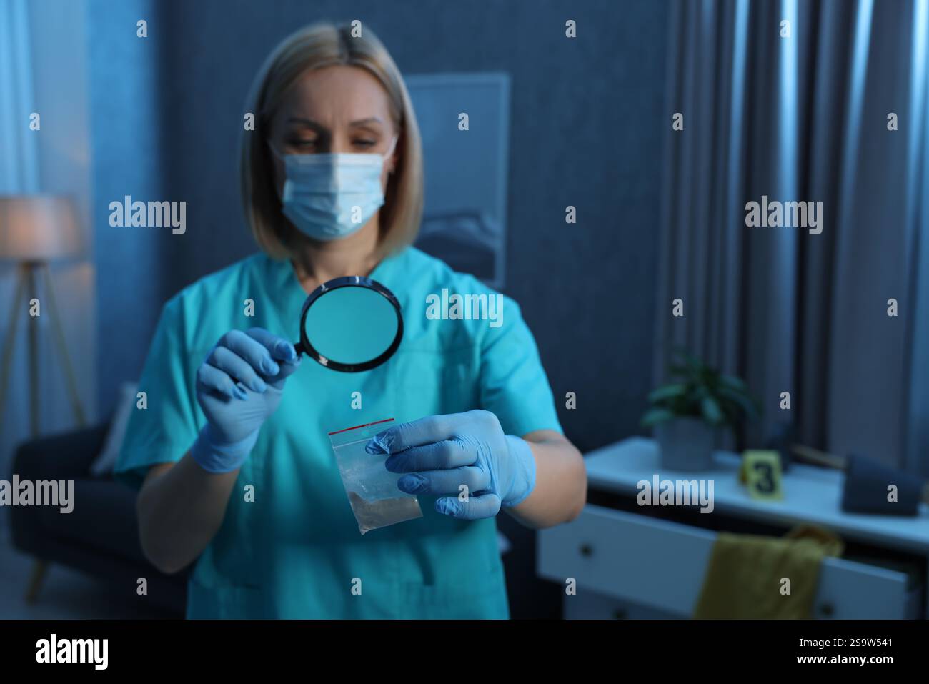 Forensic expert examining plastic bag with drug powder through ...