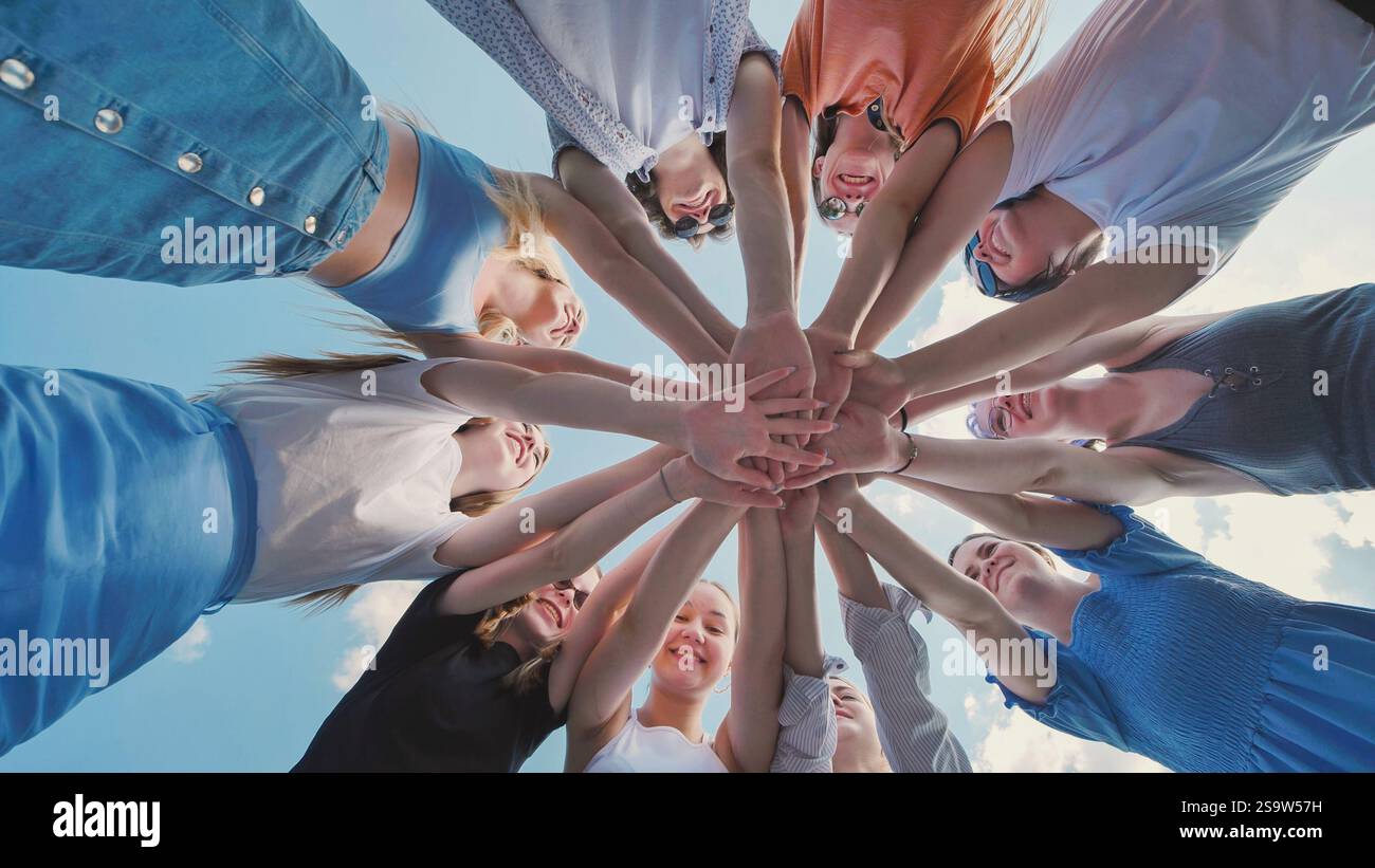 School friends come together in a circle, joining hands to represent unity, teamwork, and ...