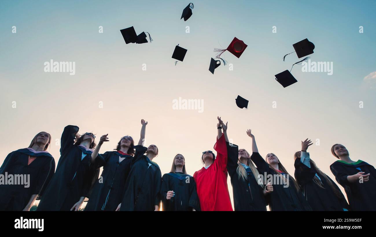 Group of cheerful graduates celebrating their graduation by tossing ...