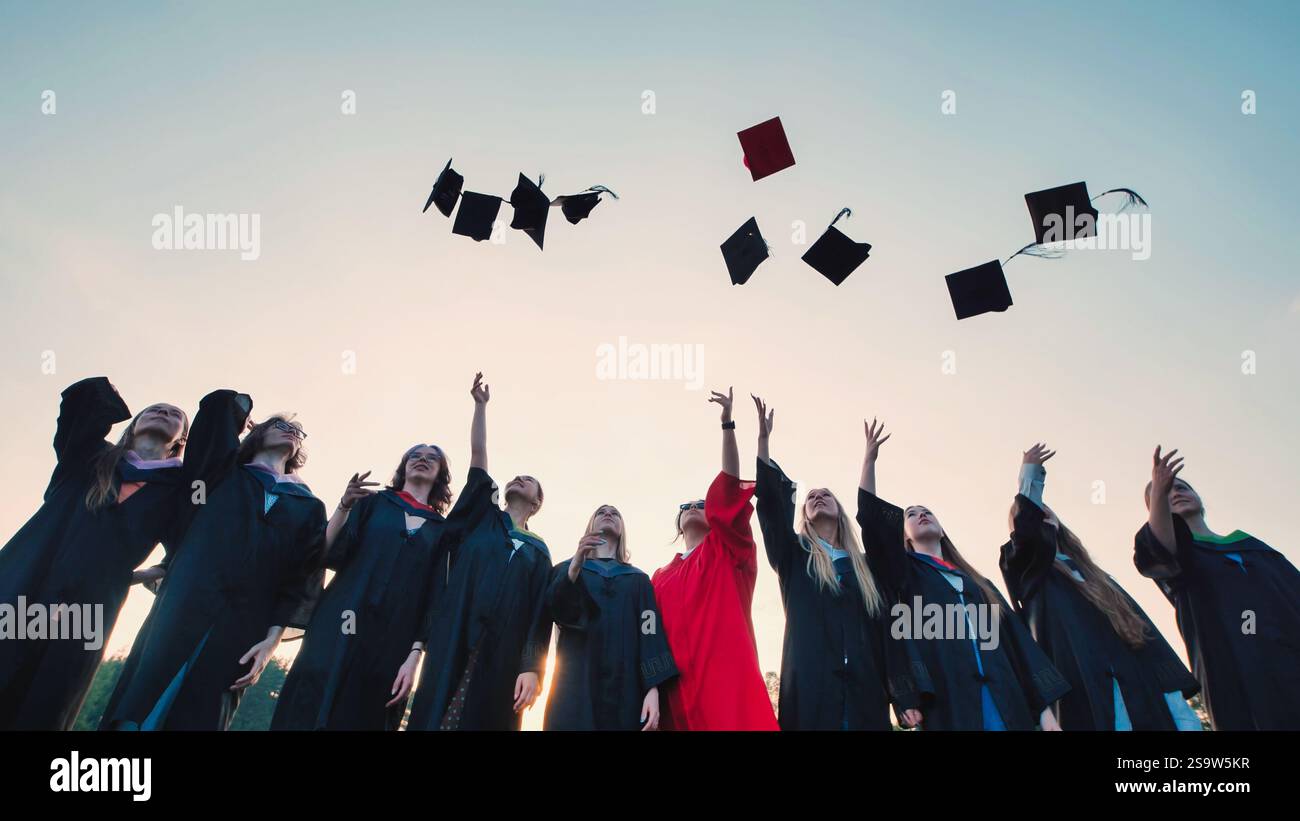 Students celebrating academic achievement by tossing graduation caps ...