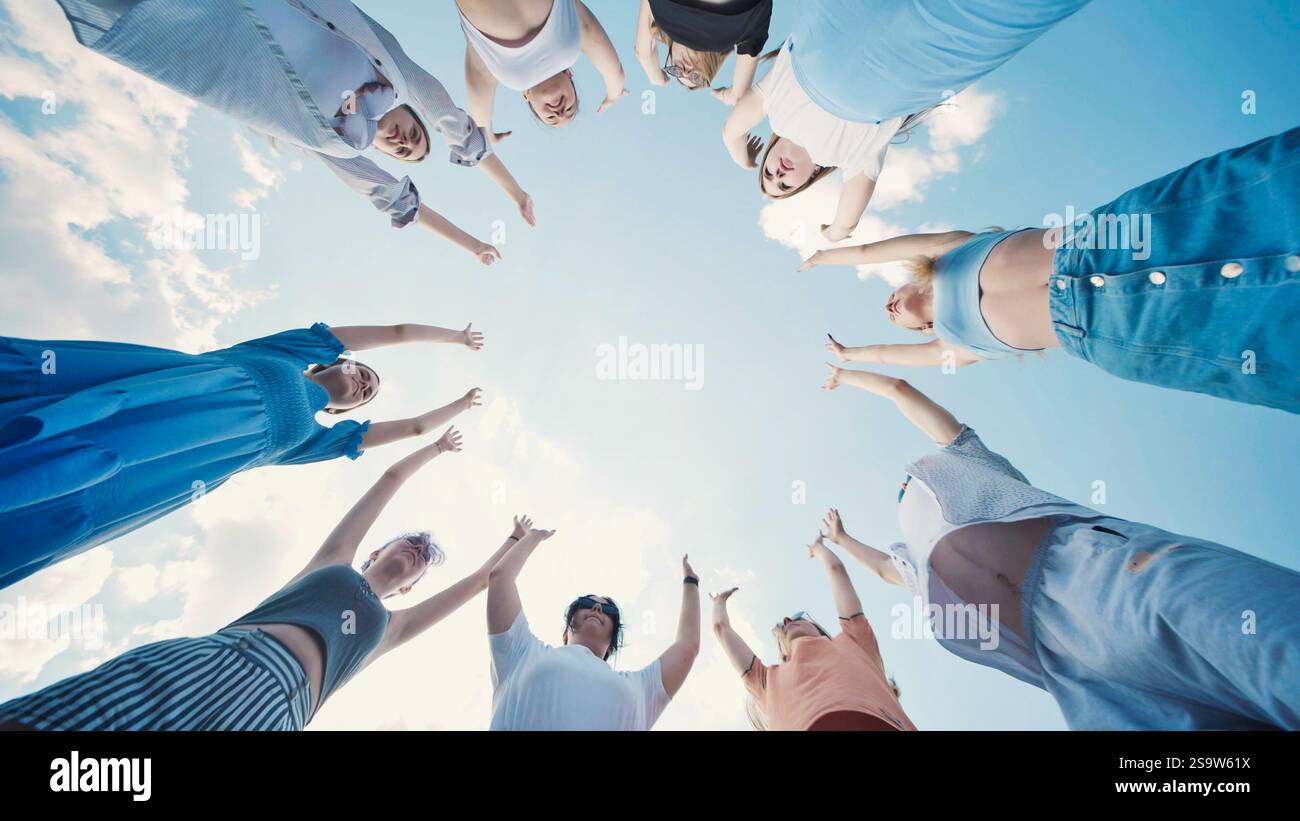 Students joining hands in a circle, raising their arms in unity and ...