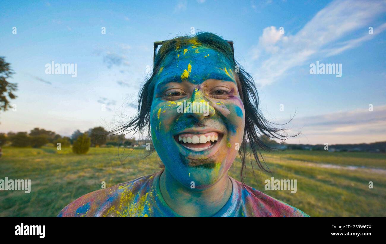 Young person laughing with colorful powder paint covering face and ...