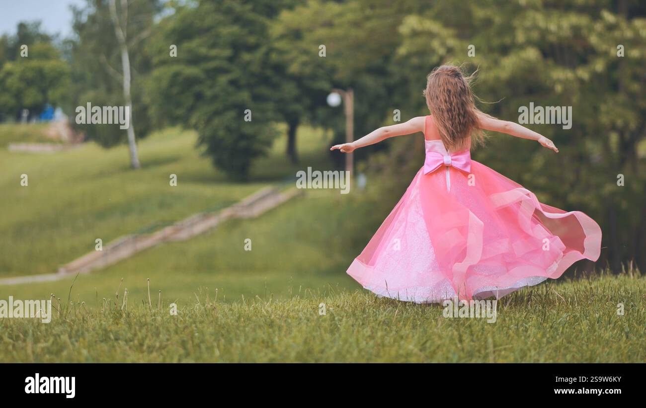 Girl spinning around with open arms, wearing beautiful pink dress ...