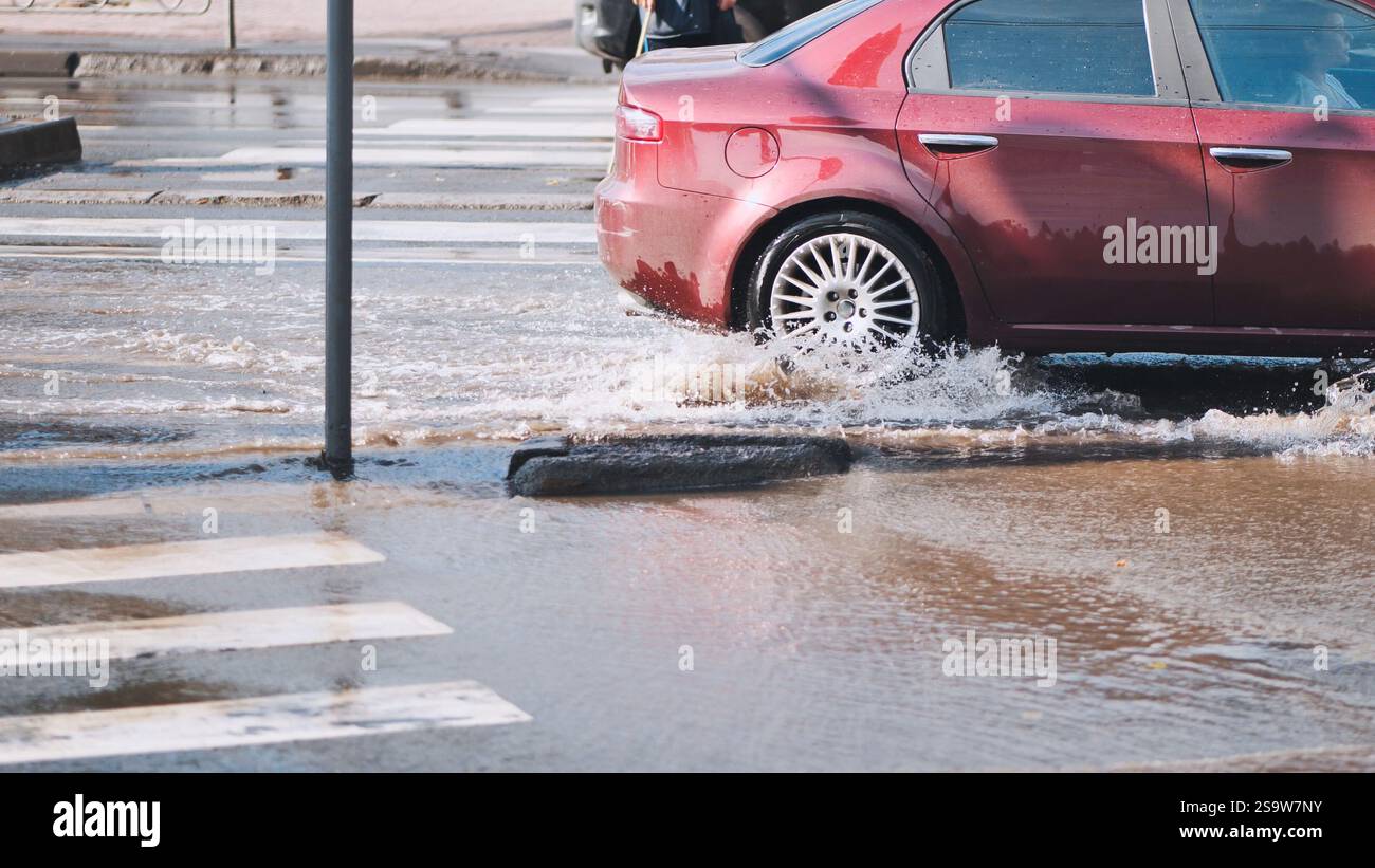 Red sedan spraying water while crossing flooded urban intersection ...