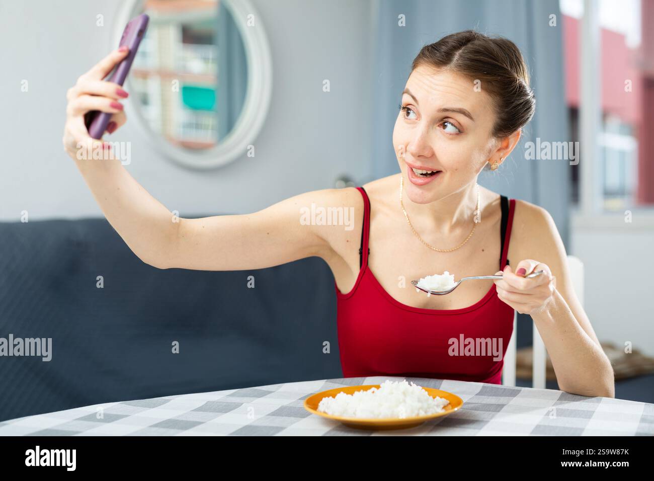 Positive woman eating rice at home and taking selfies Stock Photo - Alamy