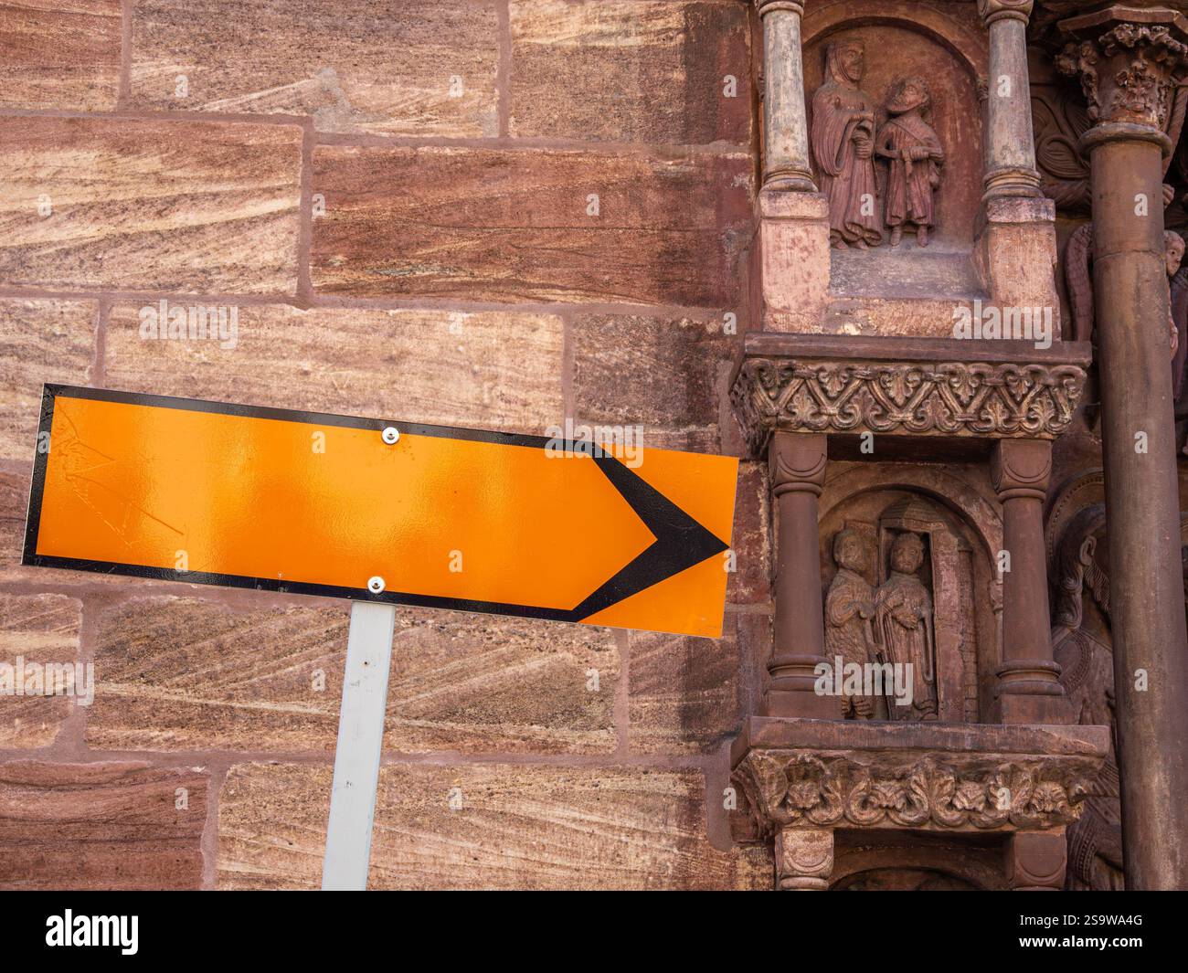 An orange directional arrow sign pointing right, positioned against a ...