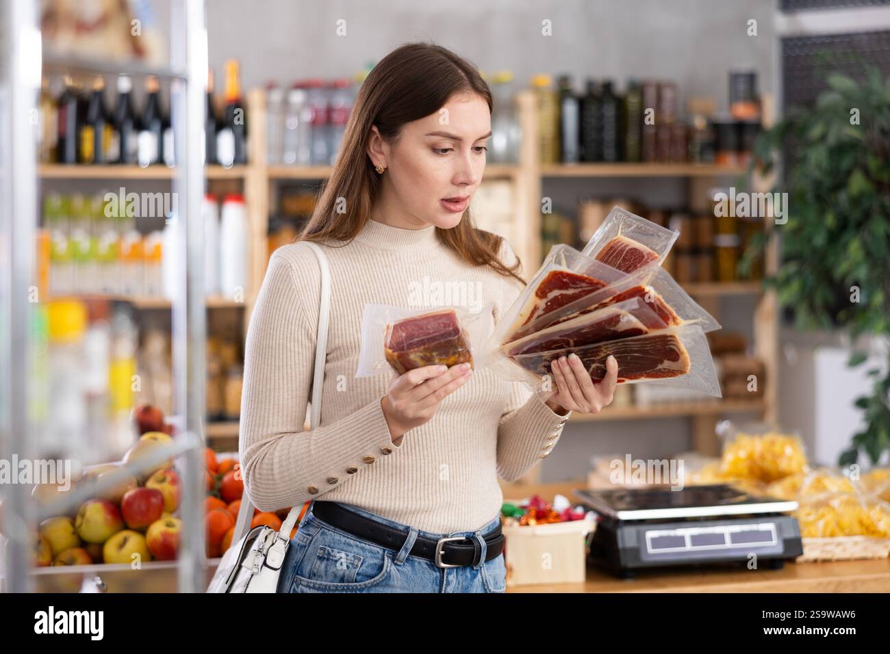Young woman choosing jamon in grocery store Stock Photo - Alamy