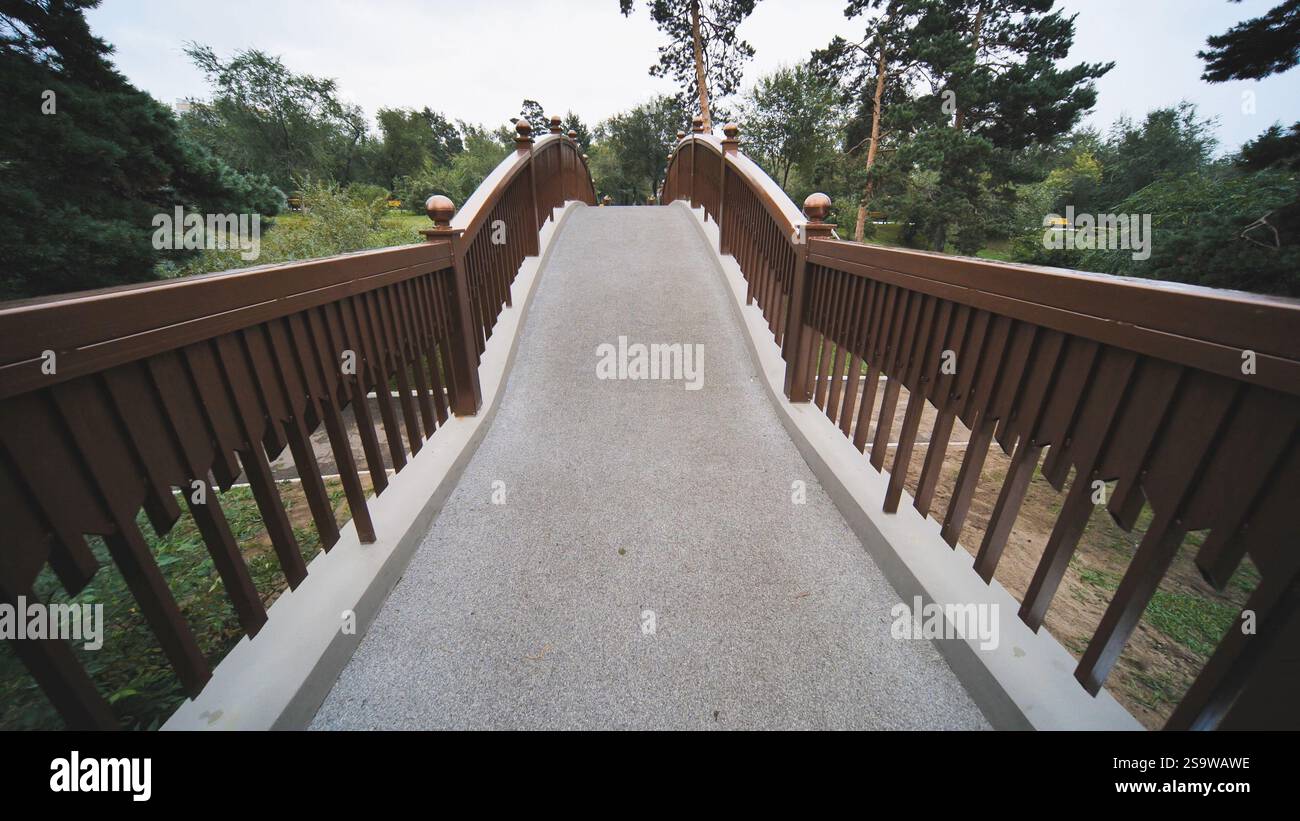 Concrete and wooden pedestrian bridge spanning narrow ravine ...