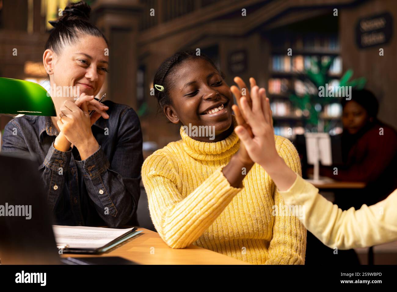 Diverse teen scholars doing high five gesture together at the end of tutoring session with ...