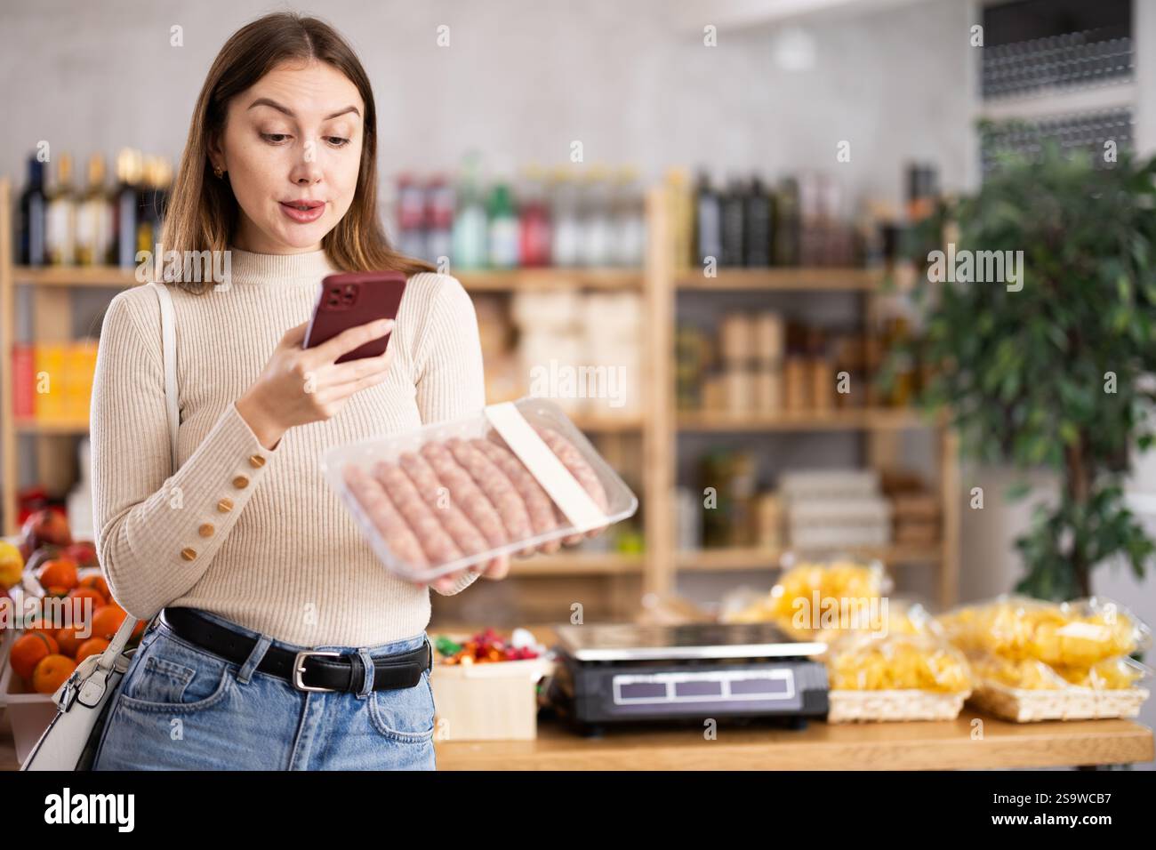Girl scan QR-code on raw pork sausages in store Stock Photo - Alamy