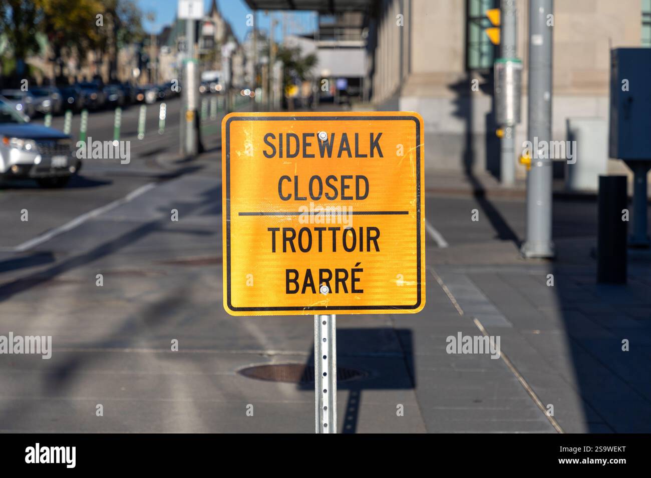 Orange sidewalk closed sign in English and French on road in downtown ...