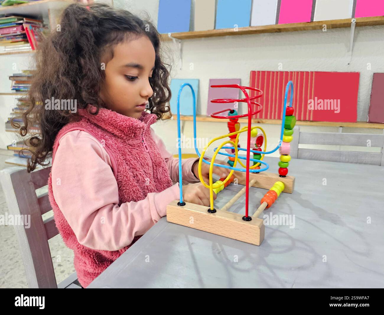 4 year old Latina brunette girl with curly hair plays an educational ...