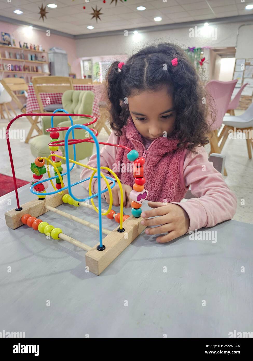 4 year old Latina brunette girl with curly hair plays an educational ...