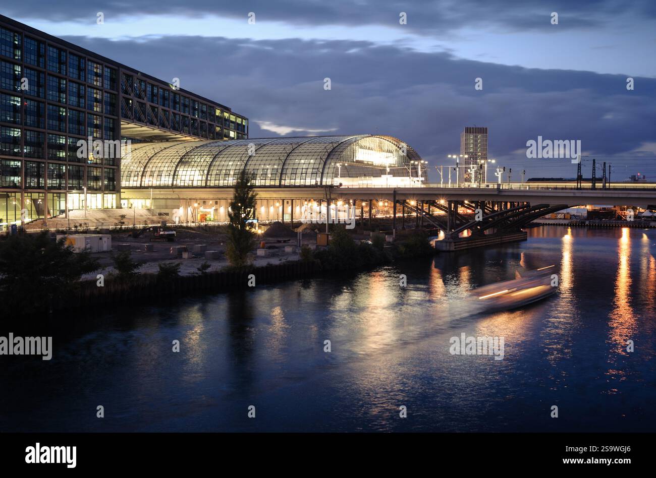 Nighttime Urban Scene with Train, Bridge, and Boat Stock Photo - Alamy