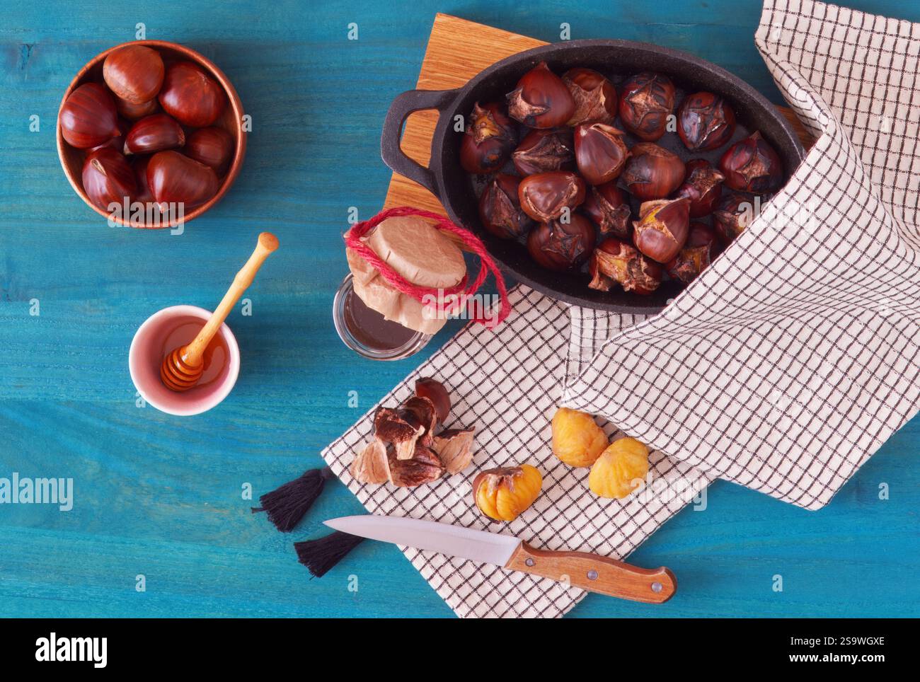 A baking dish with roasted edible chestnuts, a bowl and a jar of honey ...