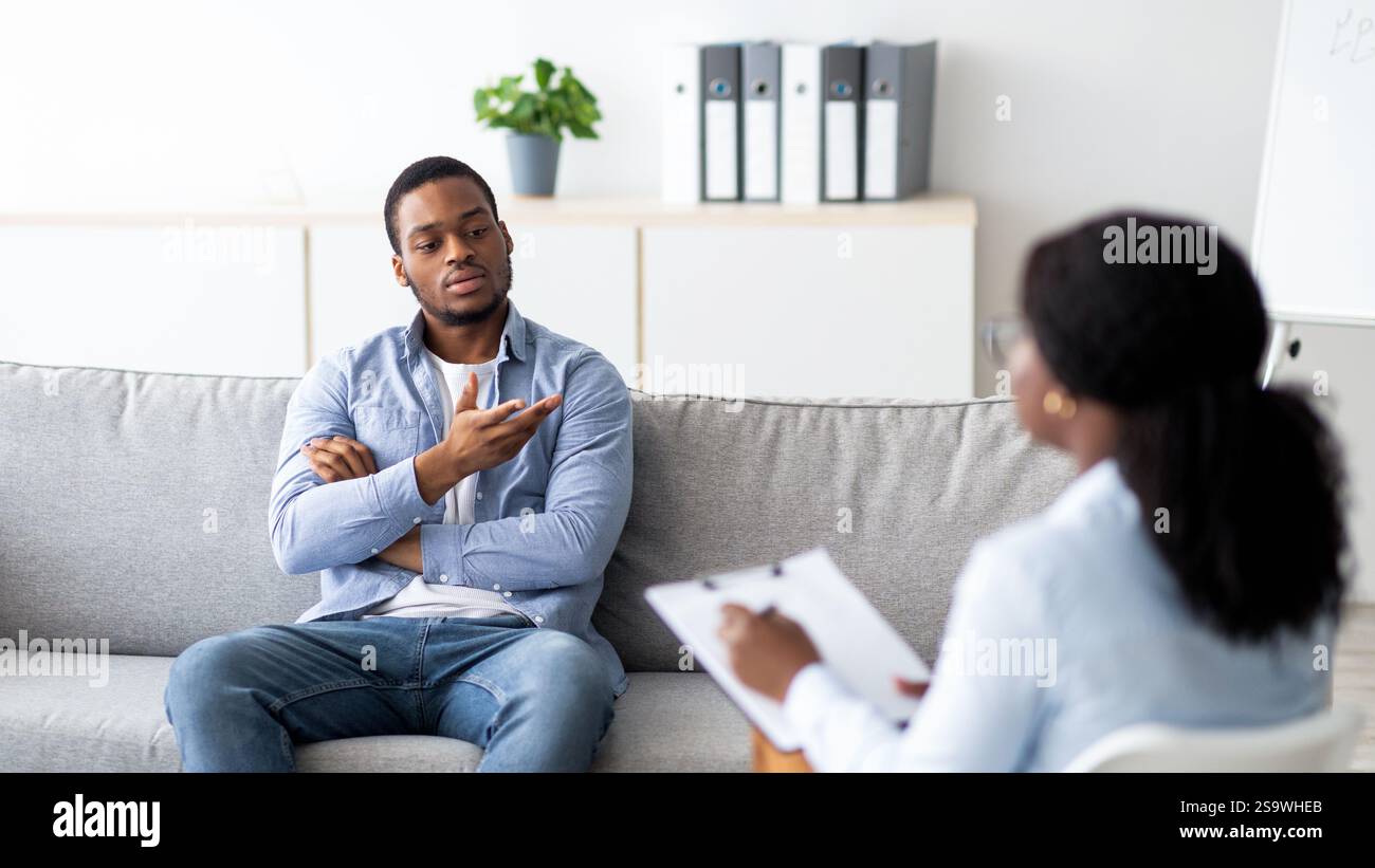 Psychologist helping black male patient, working with unhappy African ...