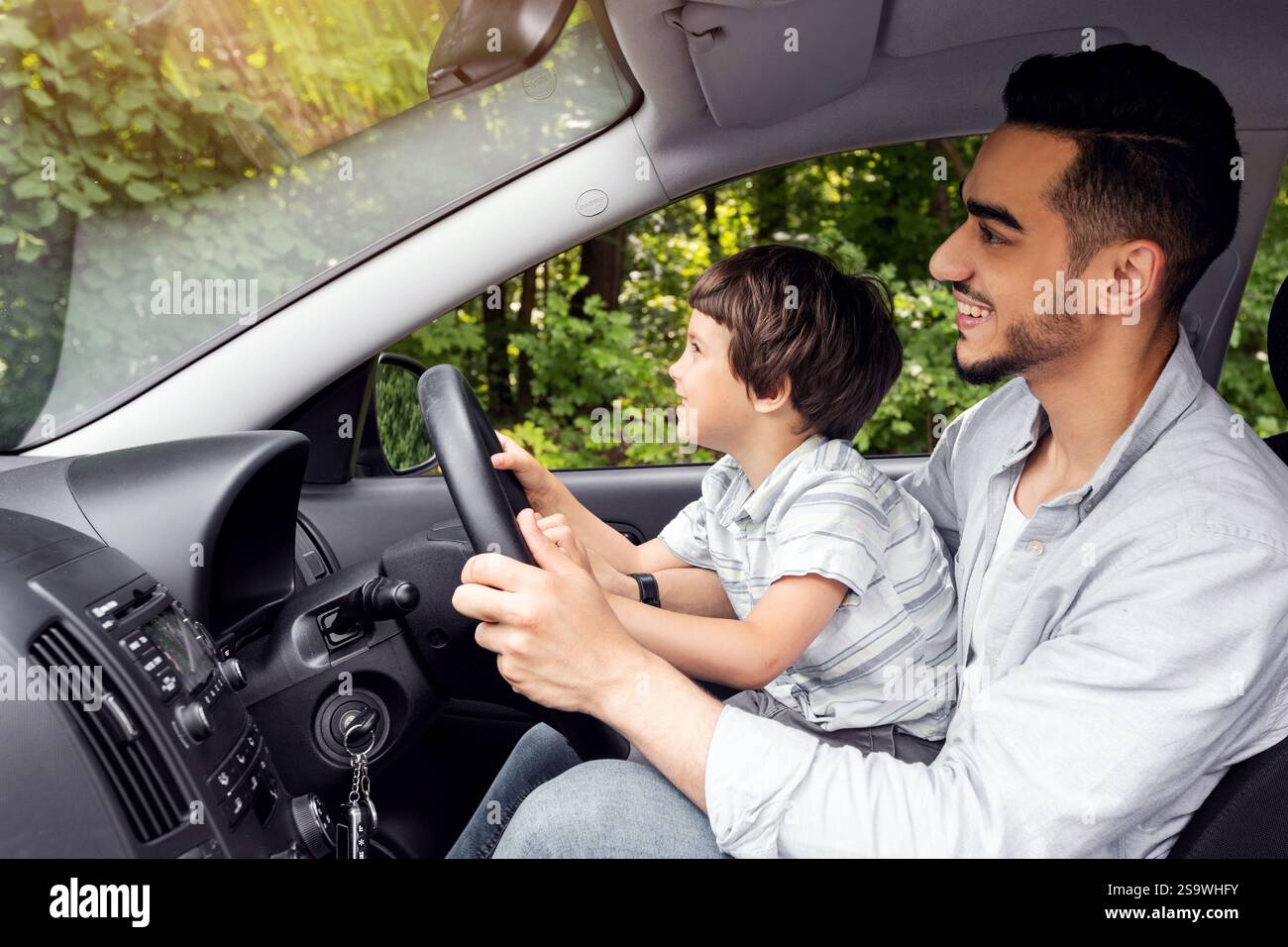 Happy smiling muslim young male teaches small kid how to drive, profile ...