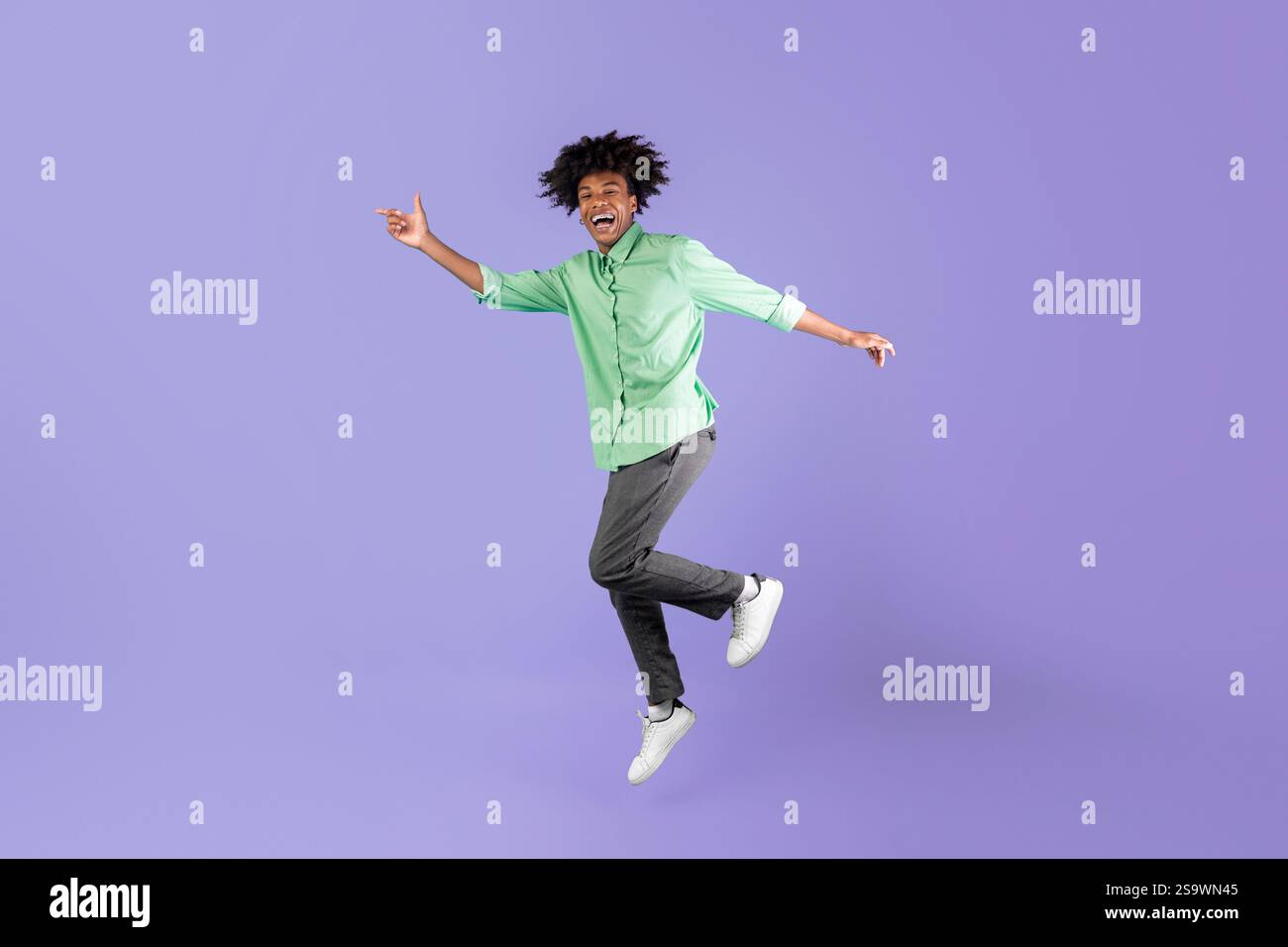 Joyful black guy jumping up in the air and showing funny figures ...