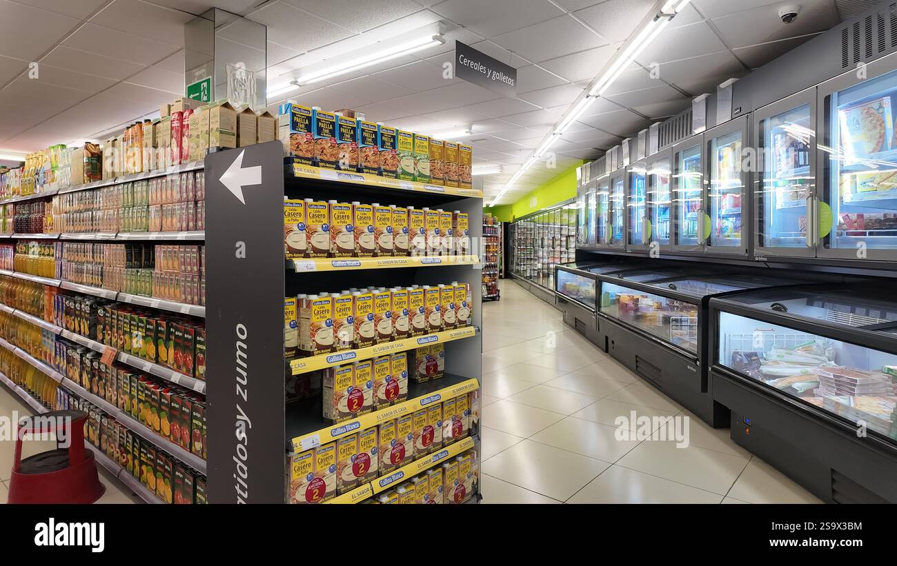 Inside a supermarket in Spain, one side features shelves stocked with ...