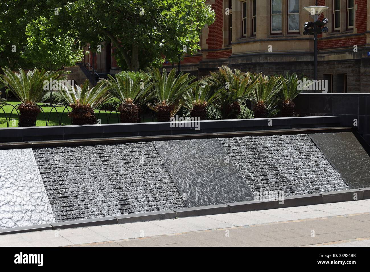 landscaped lawns and plants above a water fountain cascading across ...