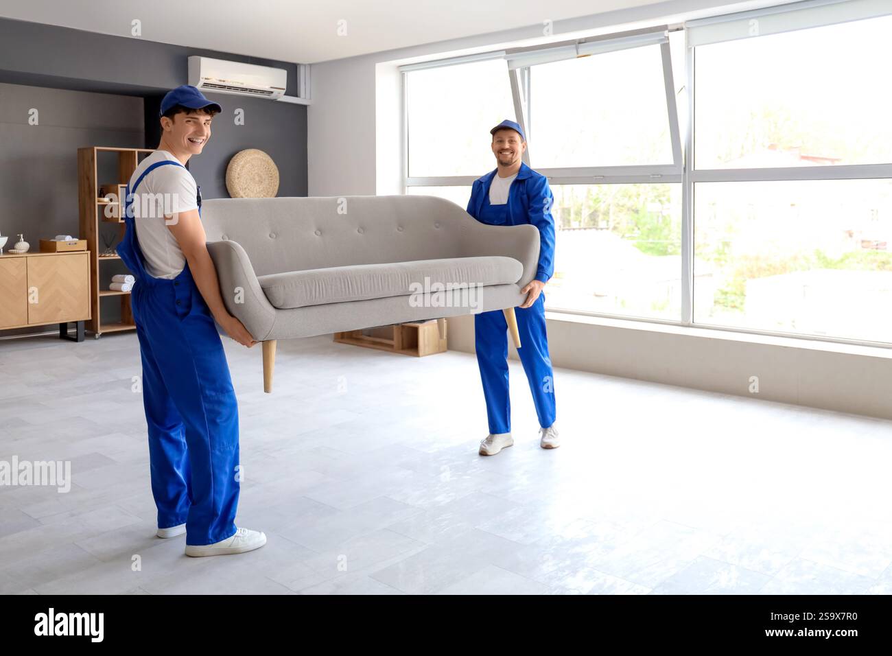 Loaders carrying couch in room Stock Photo - Alamy