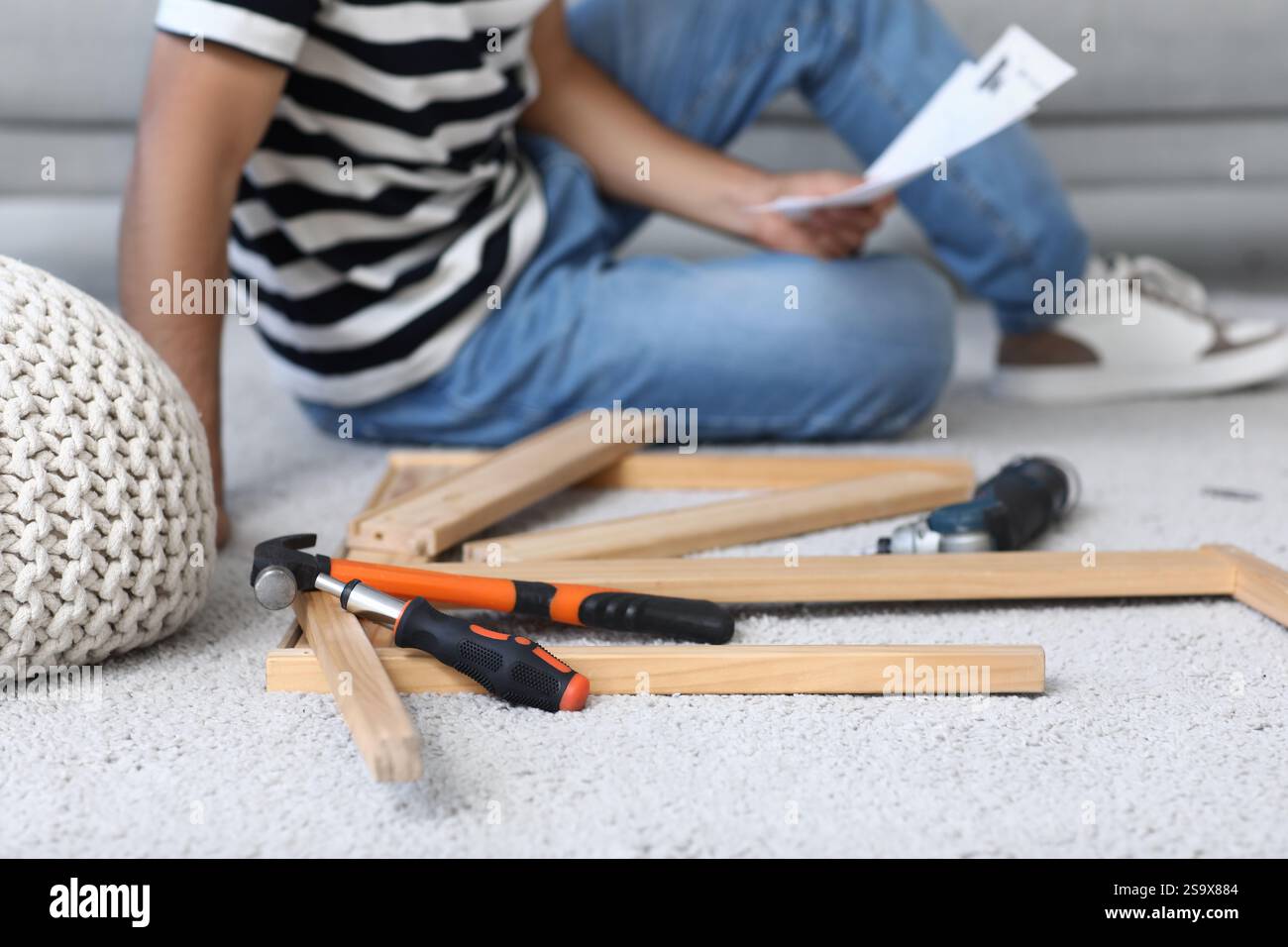 Tools with disassembled table on carpet against man with manual at home ...