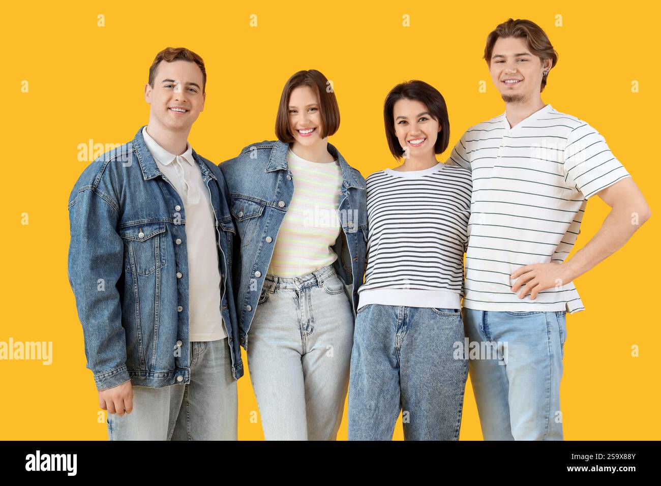 Group of young people in denim clothes hugging on yellow background ...