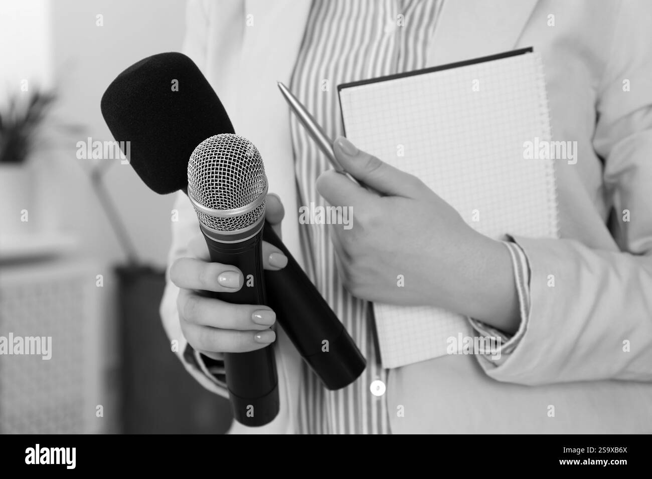 Journalist with microphones and notebook, closeup. Toned in black-and ...