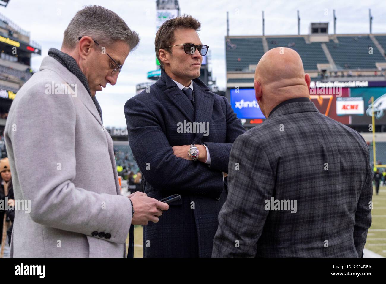 Fox Sports host Kevin Burkhard, left, and Tom Brady, center, looks on ...