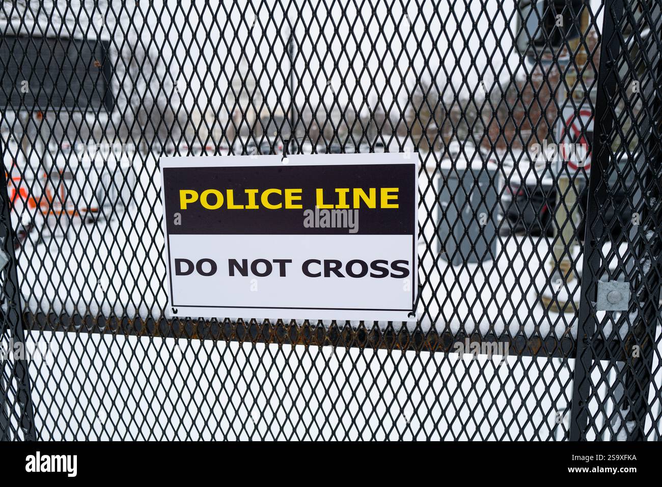 A Do Not Cross Police Line sign is posted on the metal fence ...
