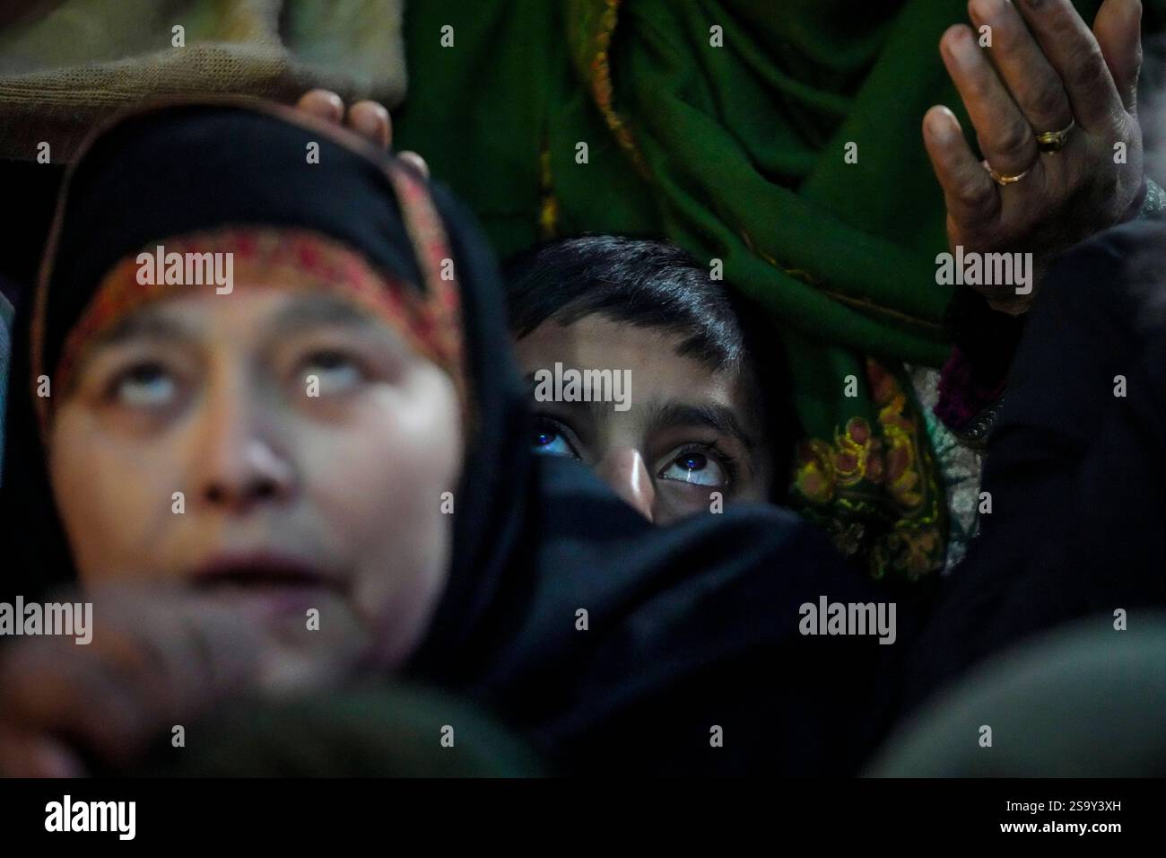 Kashmiri Muslim devotees look on and pray as a head priest displays a ...