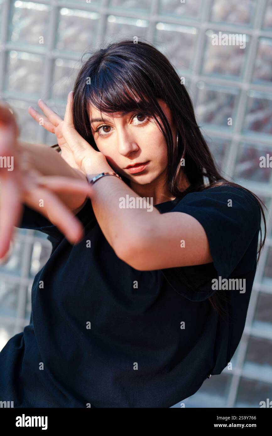 Young woman poses dramatically in front of patterned glass wall during ...