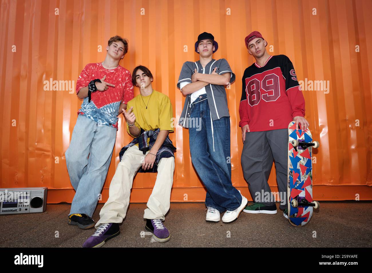 Group of Four Young Men Posing Against Orange Background Stock Photo ...