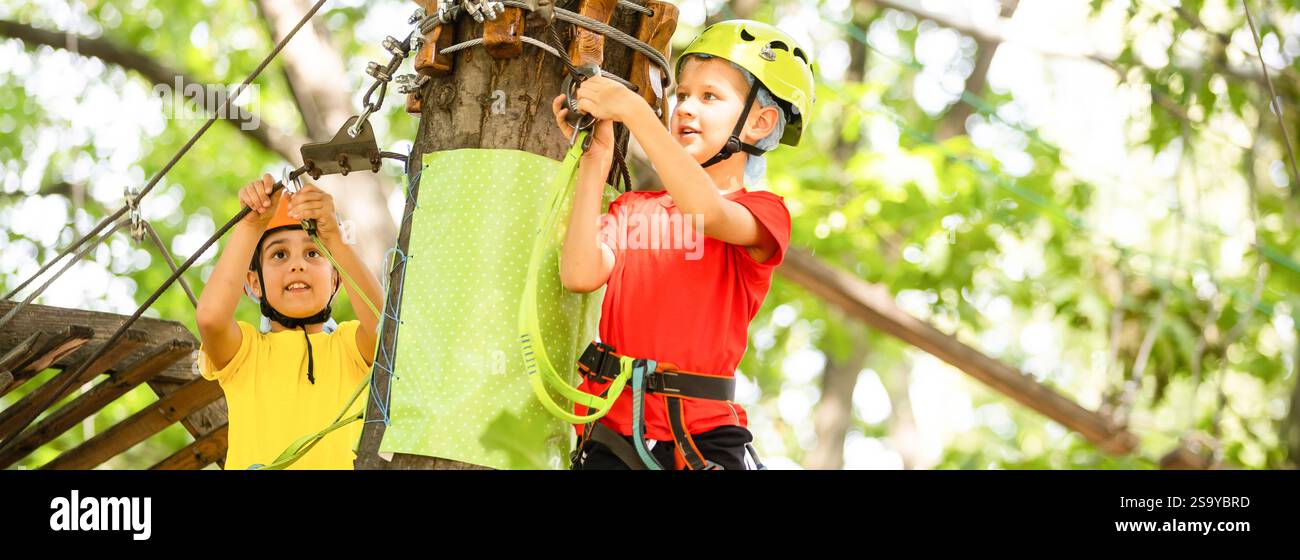 two friends in a helmet, T-shirt and shorts afraid and climbs in a rope ...