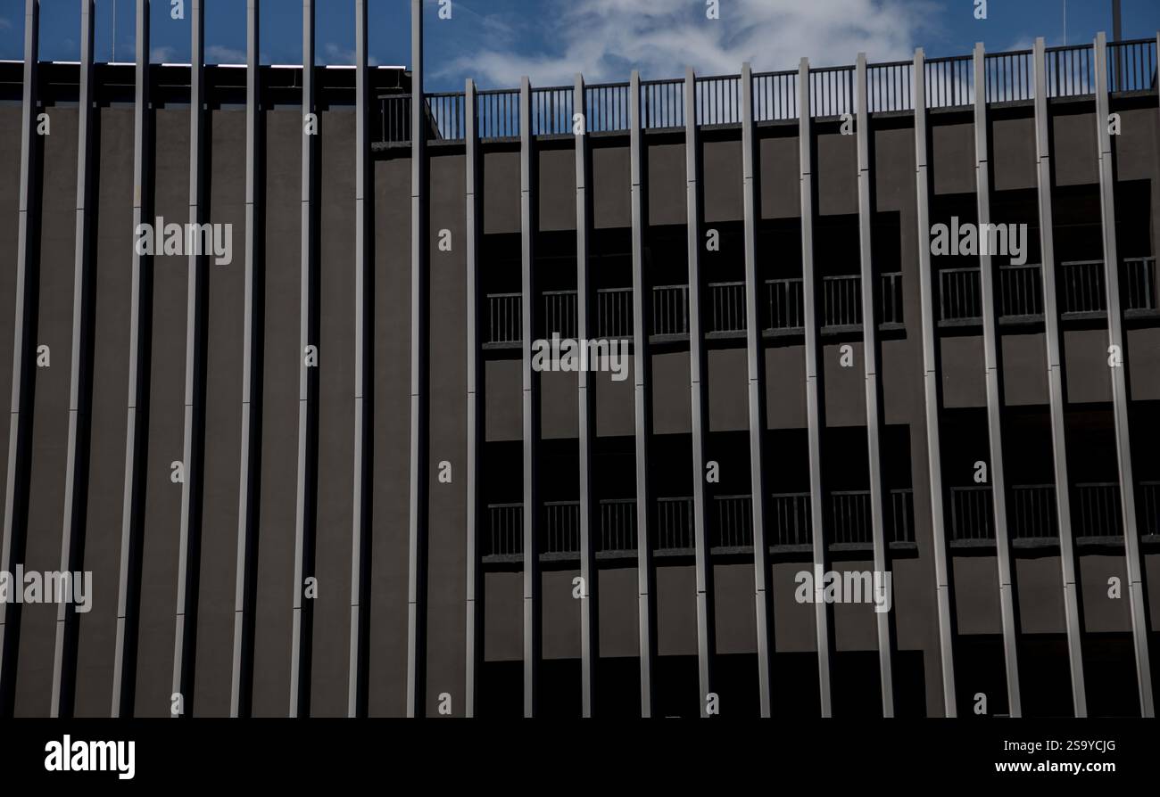 modern facade of the building is dark grey with vertical metallic slats ...