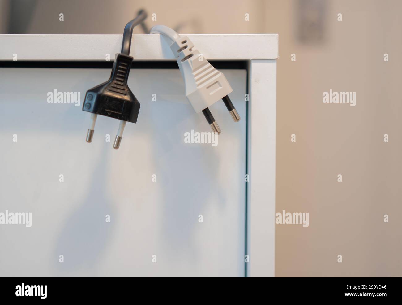 Black and white electric plugs hanging from the sideboard cabinet at ...