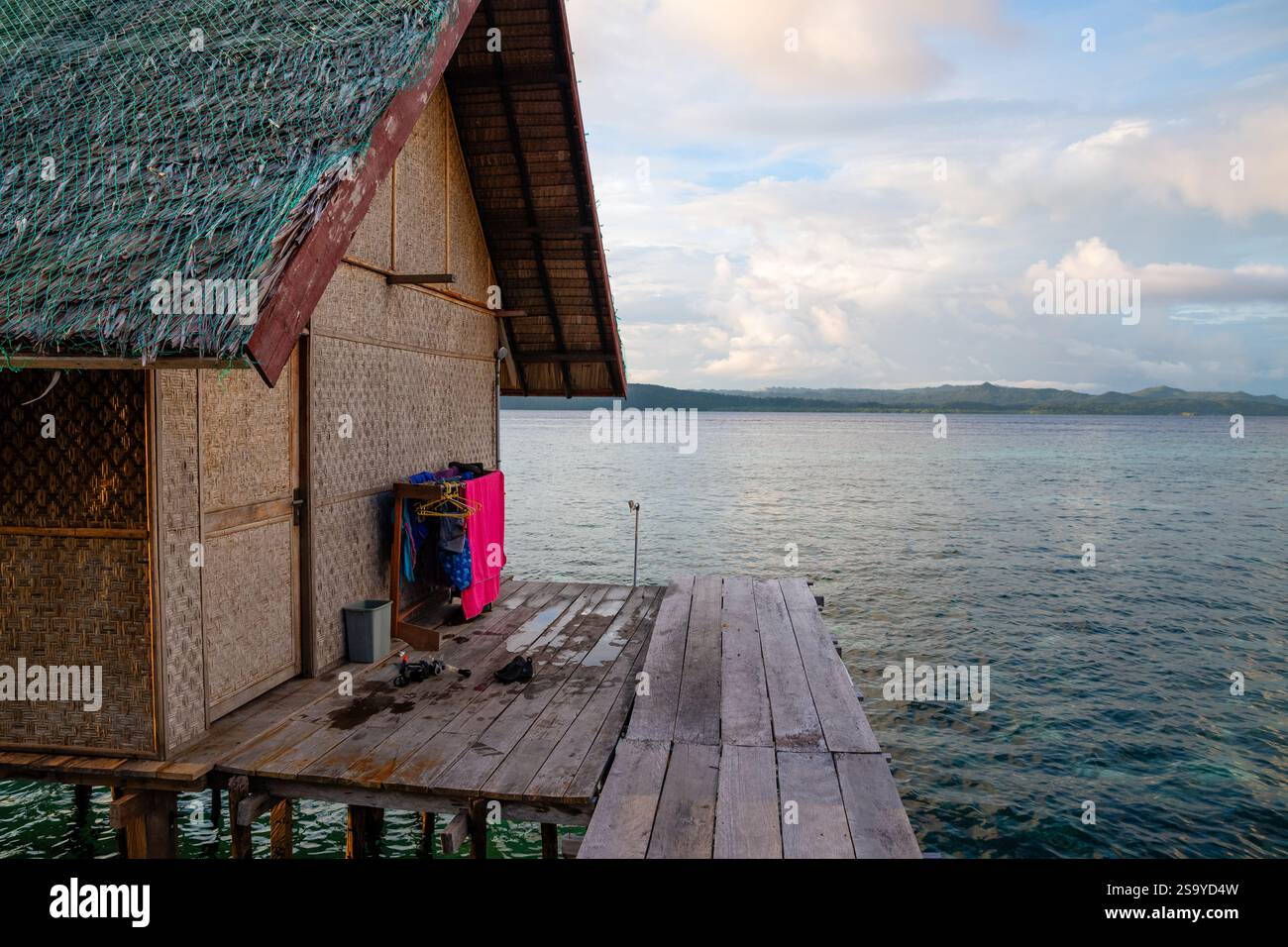 Overwater bungalow with woven walls, overlooking a calm sea and distant ...