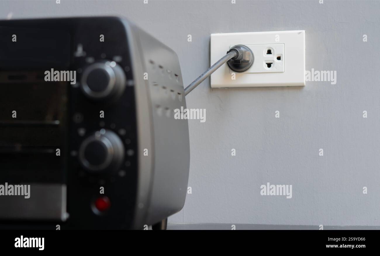 Shot image of black mini electric oven with plugin outlet power at wall ...