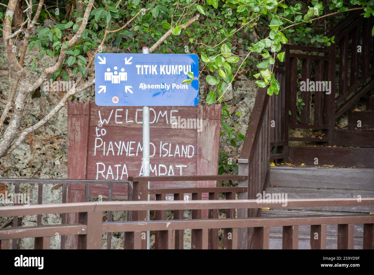 A blue "Assembly Point" sign and a rustic wooden welcome sign for ...