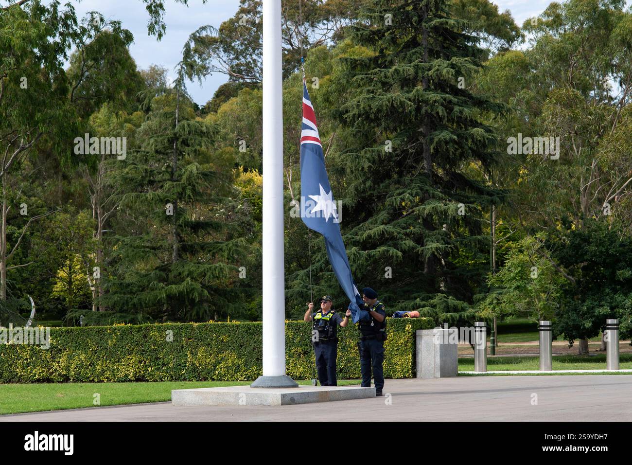 Two members of the Australian Federal Police lower the Australian Flag ...