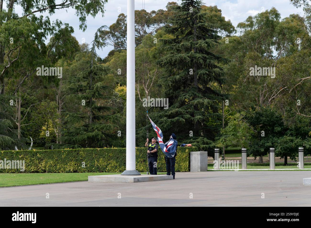 Two members of the Australian Federal Police lower the Australian Flag ...