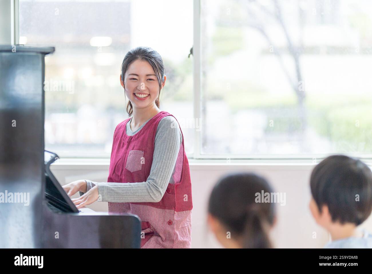 Nursery school children singing with piano player Stock Photo - Alamy