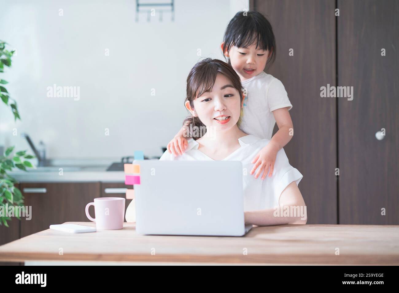 Telework image Woman working in living room and child playing Stock ...