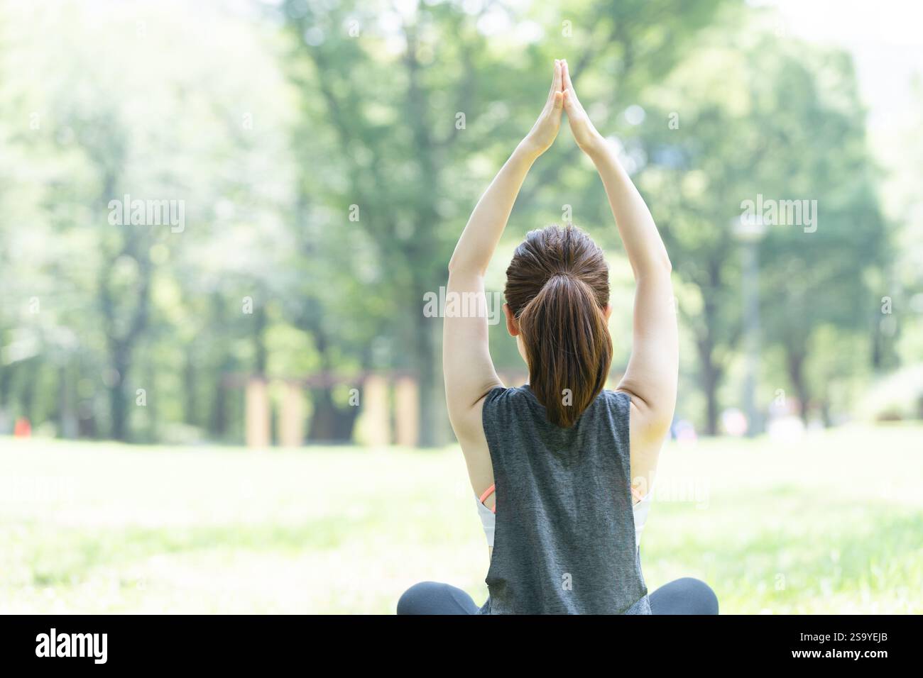 Woman doing yoga/stretching in park, back view Stock Photo - Alamy