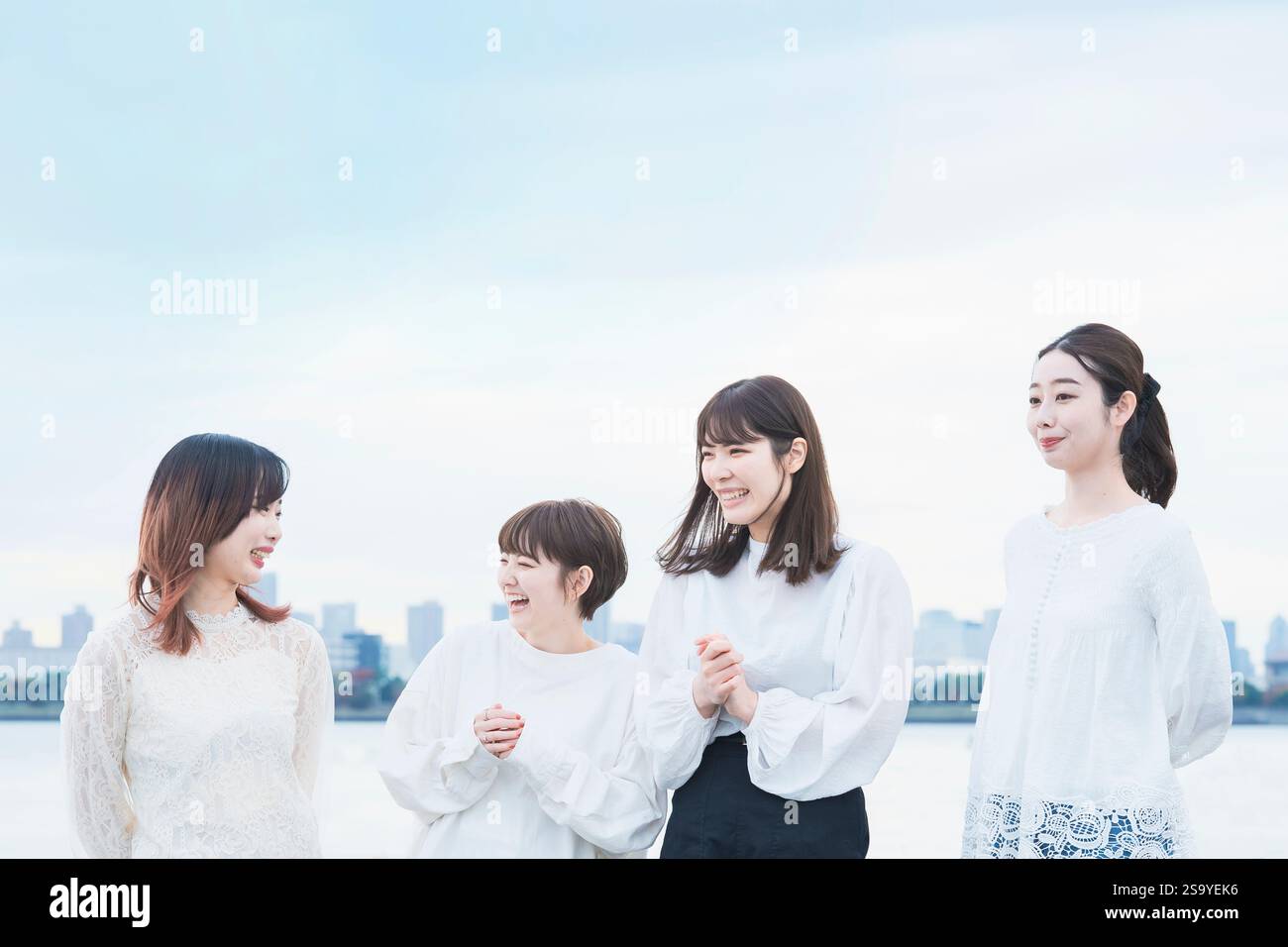 Four women smiling and talking Stock Photo - Alamy