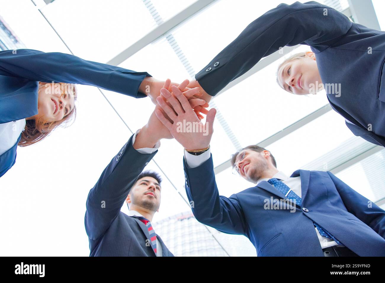 A team of businesspeople overlapping members' hands to strengthen unity ...