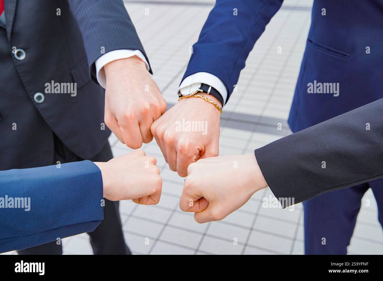 A team of businesspeople overlapping members' hands to strengthen unity ...