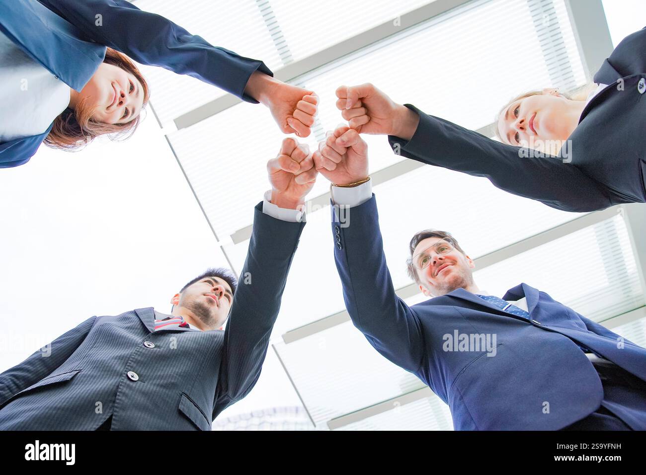 A team of businesspeople overlapping members' hands to strengthen unity ...